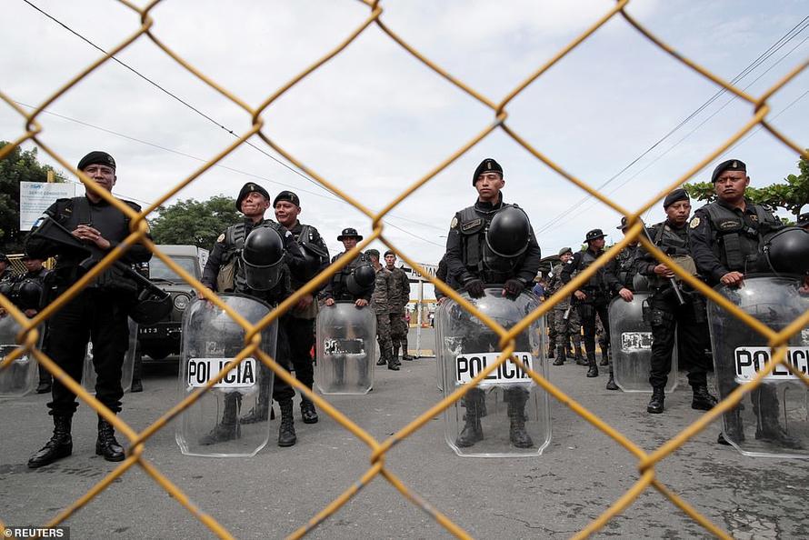 5209040-6295861-Police_stand_in_riot_gear_at_Mexico_s_border_with ...